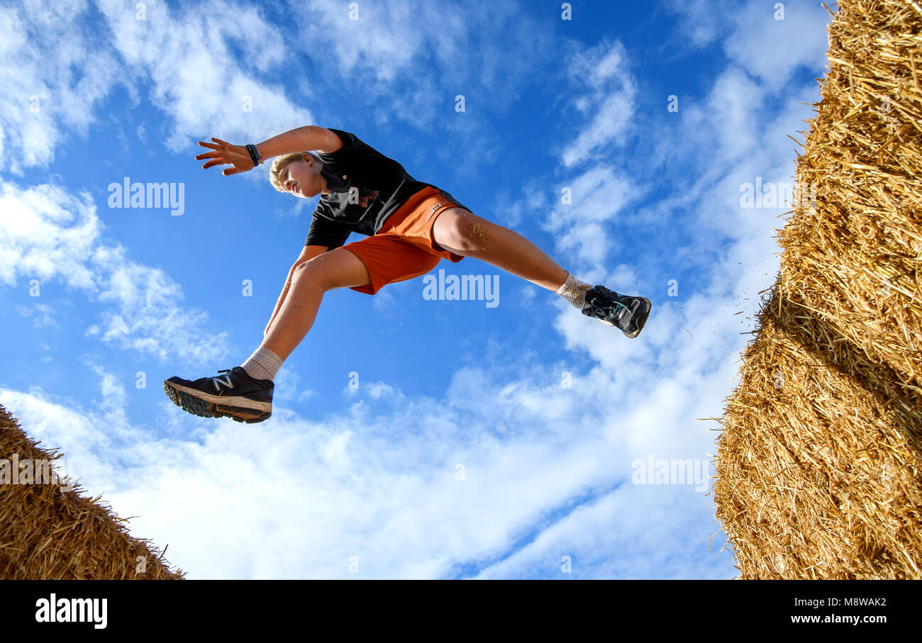 Blond boy jumping straw bales Stock Photo - Alamy