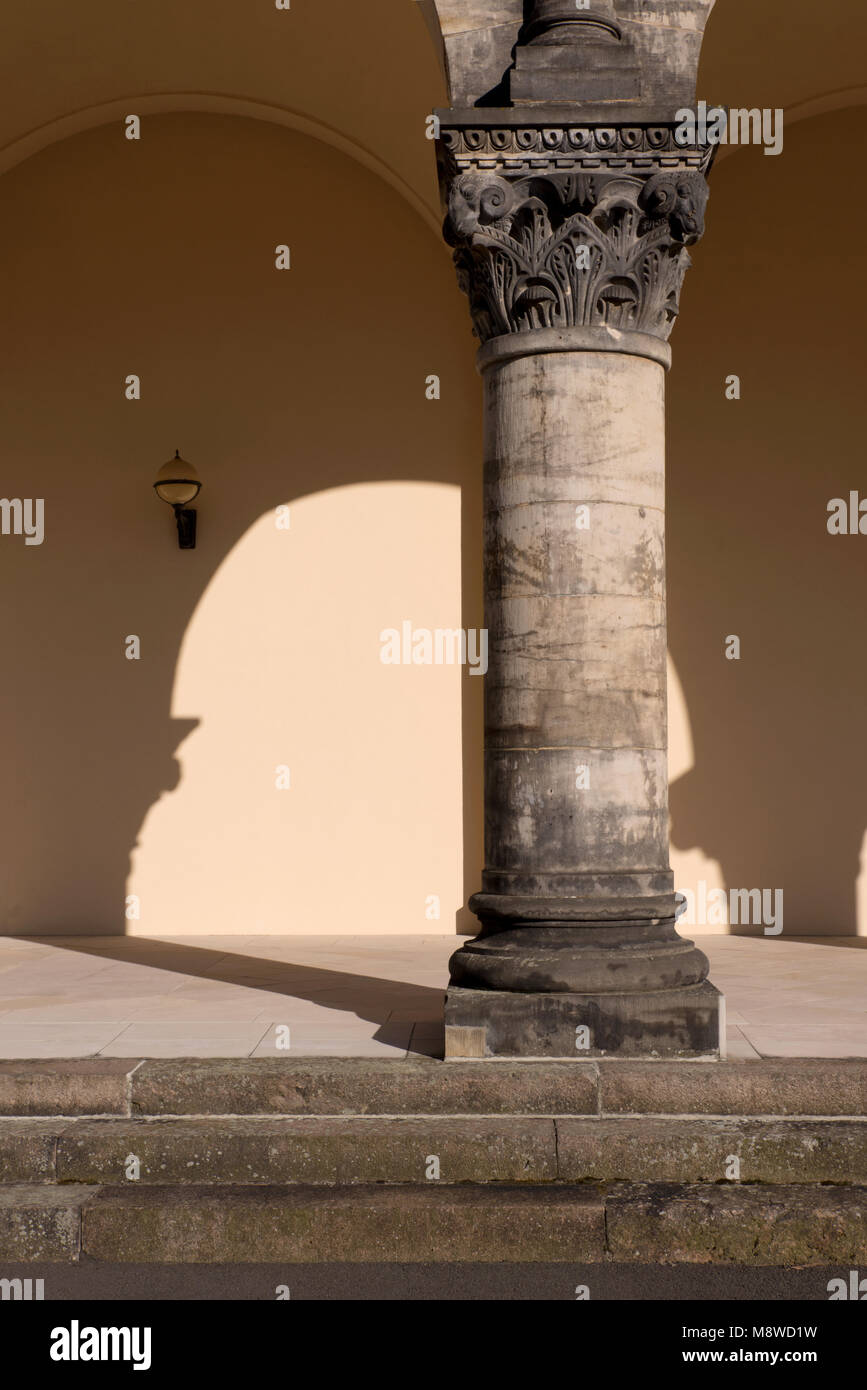Close-up of bottom single old stone column and blank wall and sunlight ...