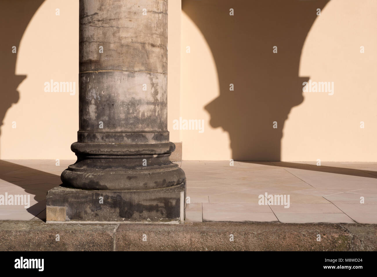 Close-up of bottom single old stone column and blank wall and sunlight ...