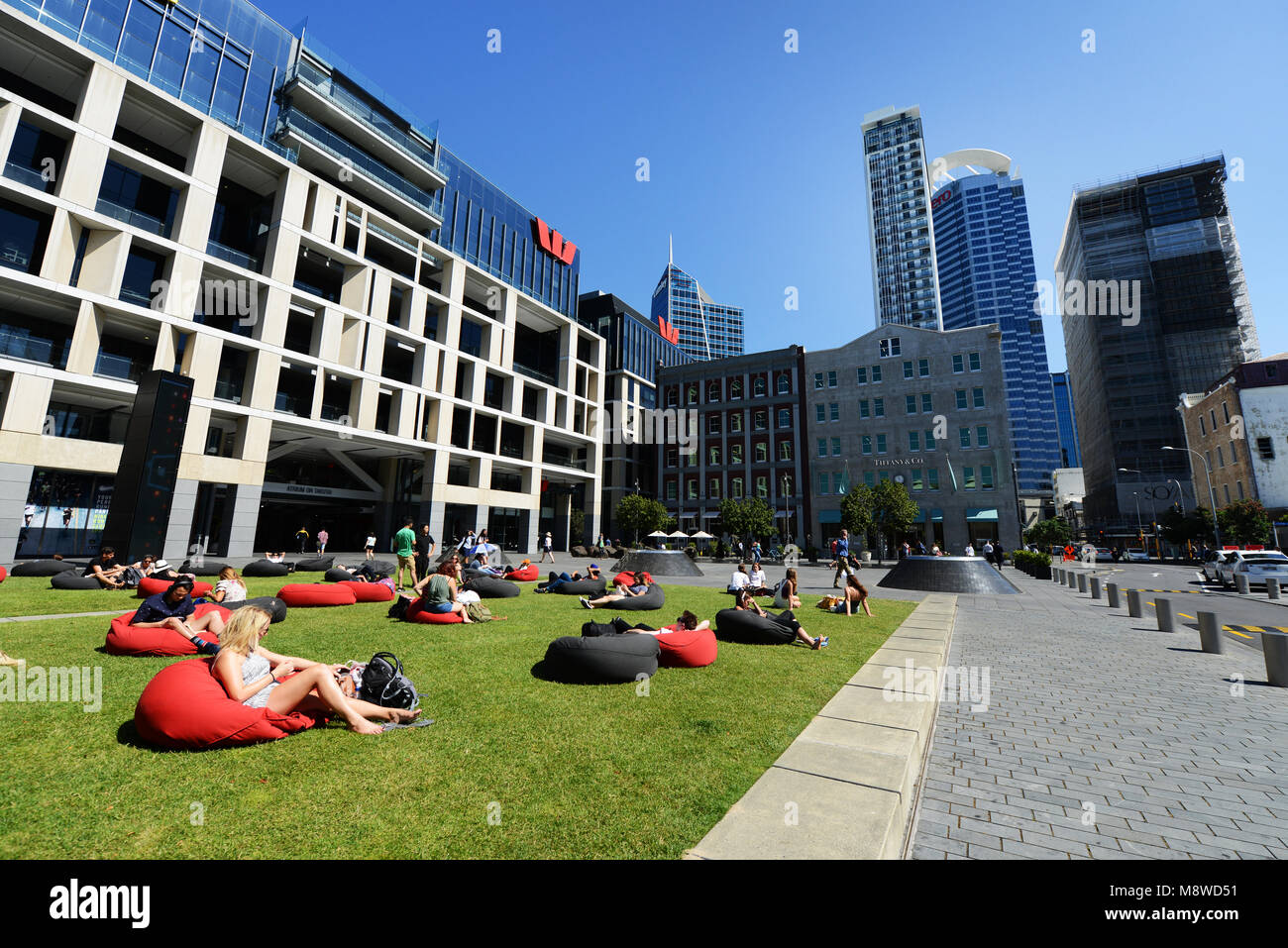 Locals relaxing on the Takutai Lawn at the Talitao square in Auckland's ...