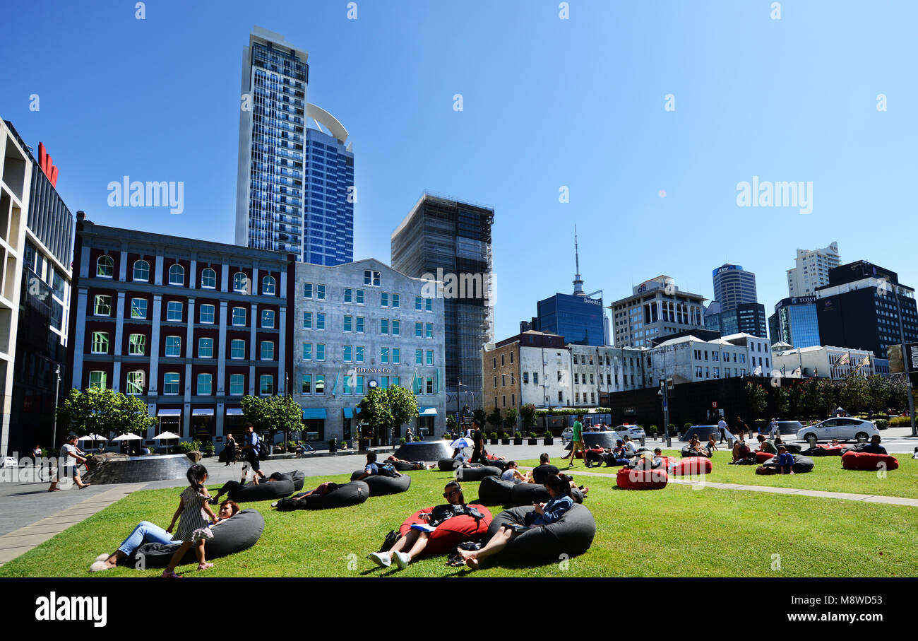 Locals relaxing on the Takutai Lawn at the Talitao square in Auckland's ...