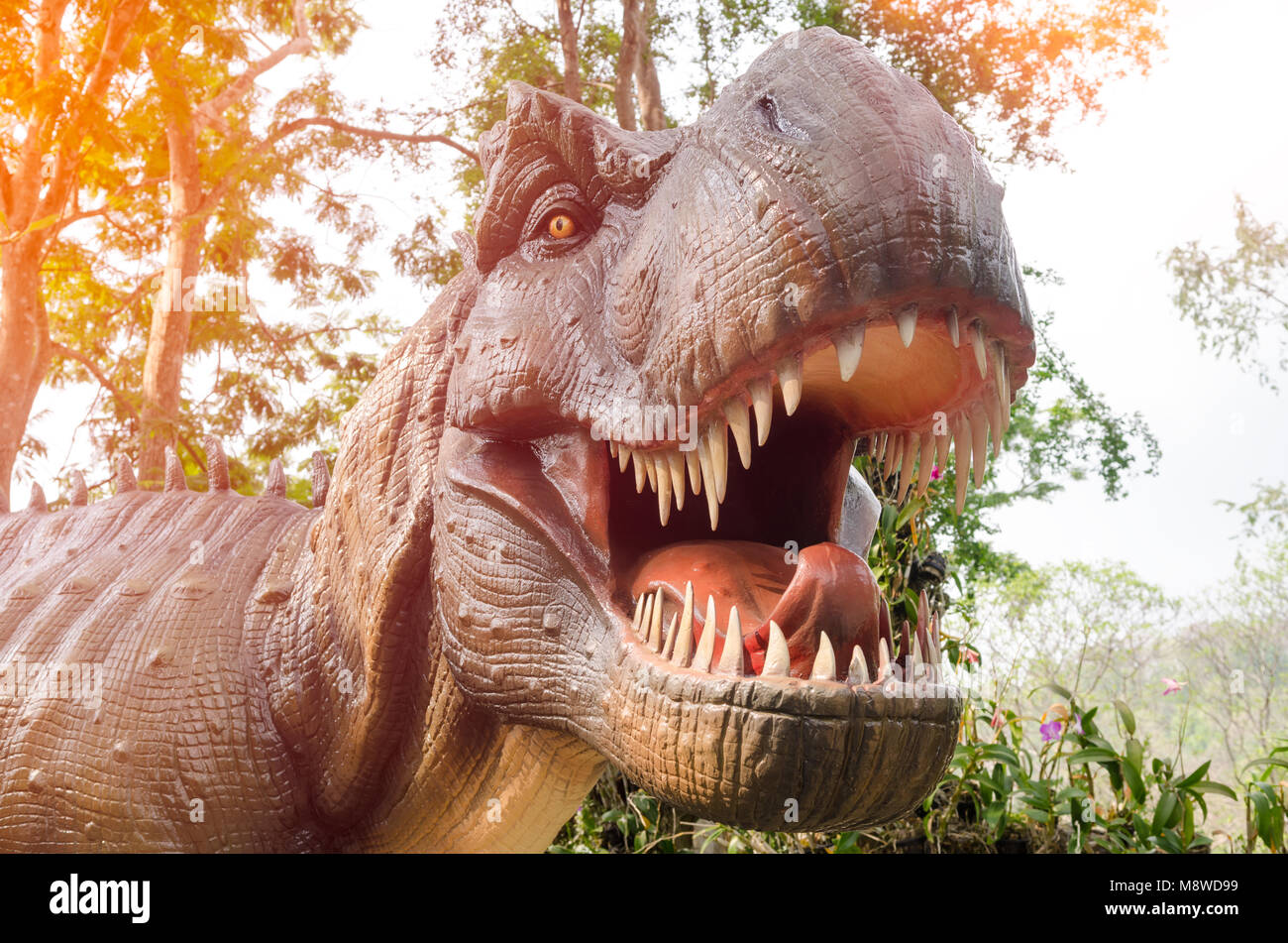 Dinosaur T - rex statue with orange light in nature Stock Photo - Alamy