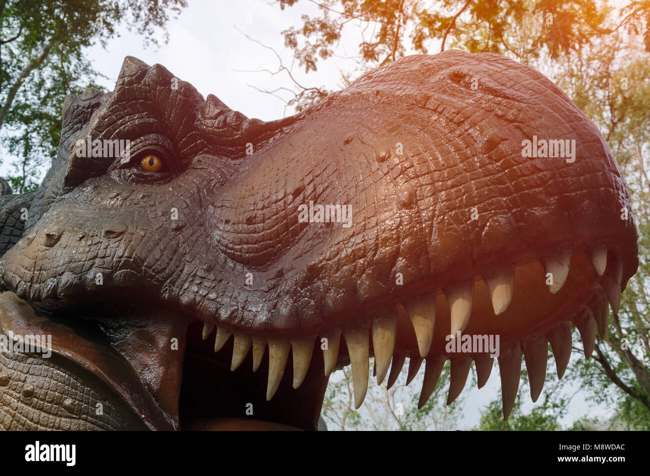 Dinosaur T - rex statue with orange light in nature Stock Photo - Alamy