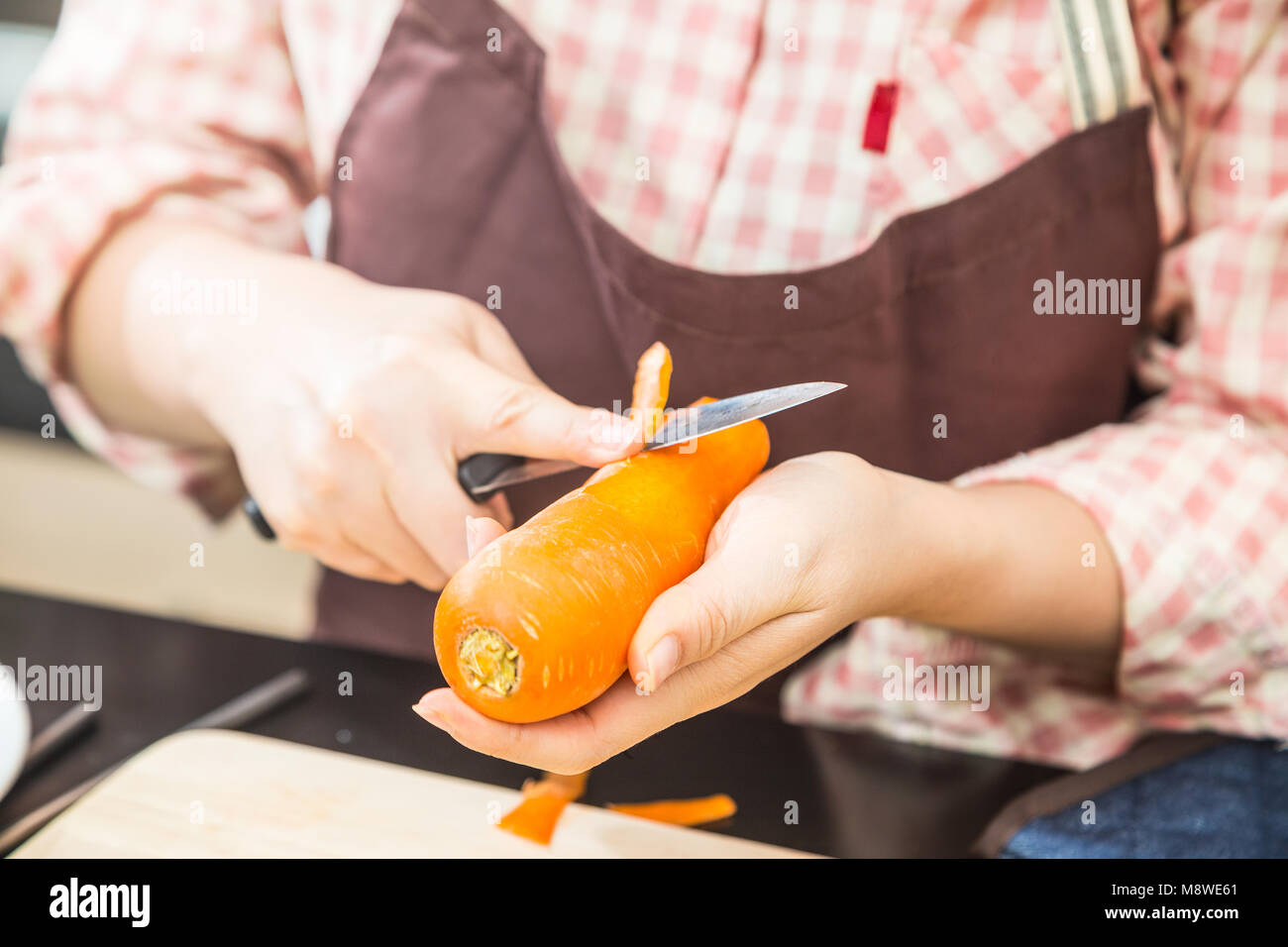 Female cook cutting fresh carrot to make delicious salad, showing her ...