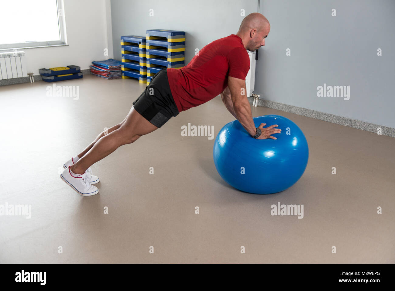 Man Stretches On Ball In A Gym And Flexing Muscles - Muscular Athletic ...