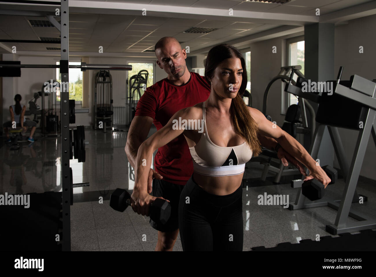 Young Couple Working Out In Gym - Doing Shoulders Exercise With Dumbbells Stock Photo - Alamy