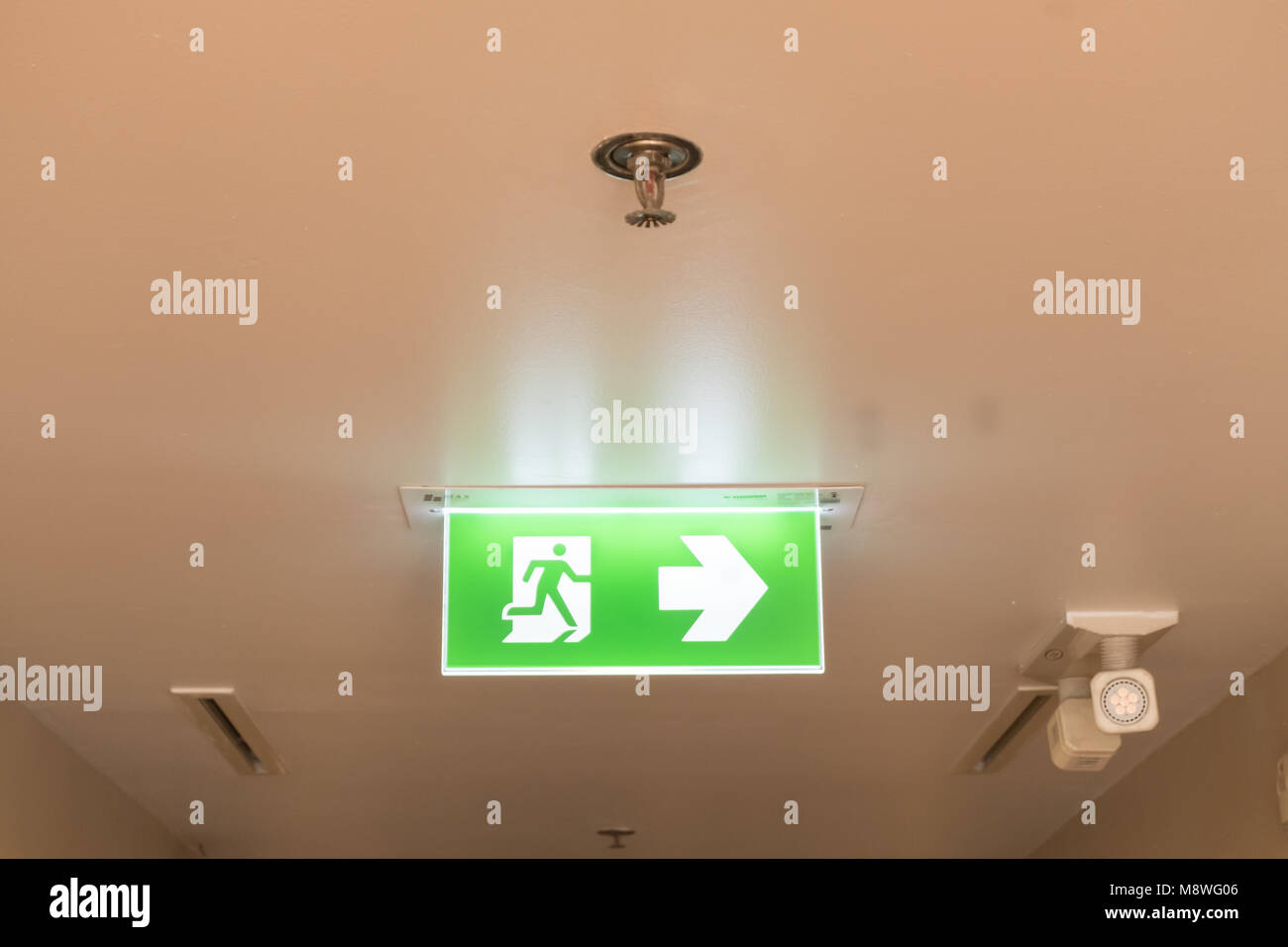 Green emergency exit sign showing the way to escape Stock Photo - Alamy