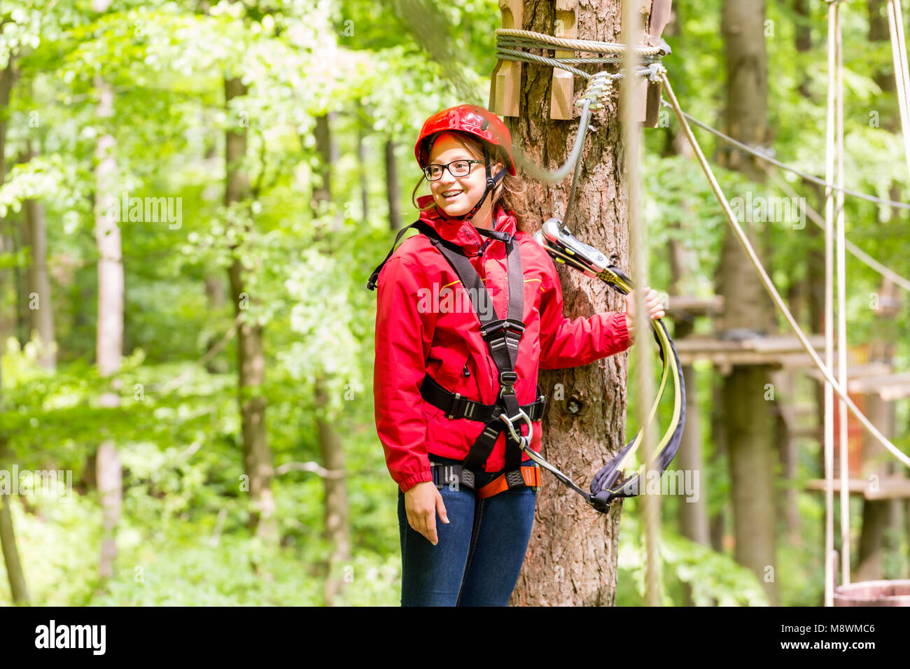 Teenage child enjoying climbing on a high rope course Stock Photo - Alamy