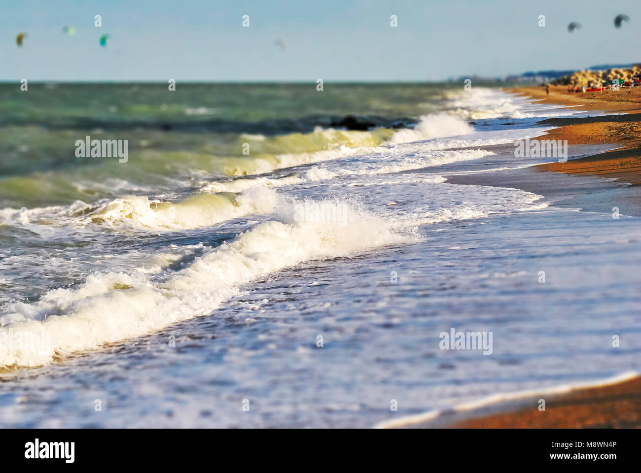 Large foamy waves crash on a beach on a sunny day with rough seas. Tilt ...