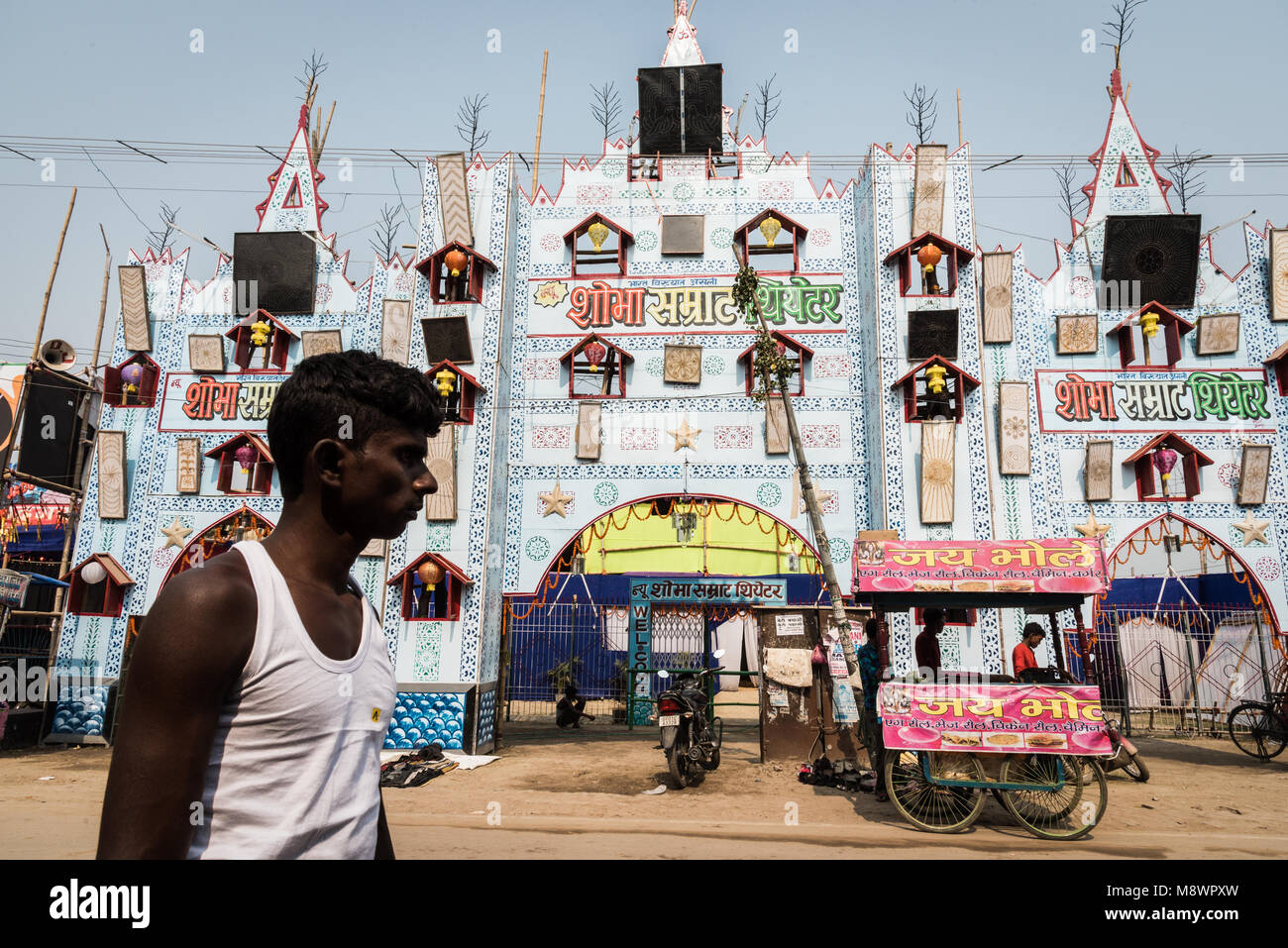 A man walking down a street in front of a facade at the Sonepur Mela ...