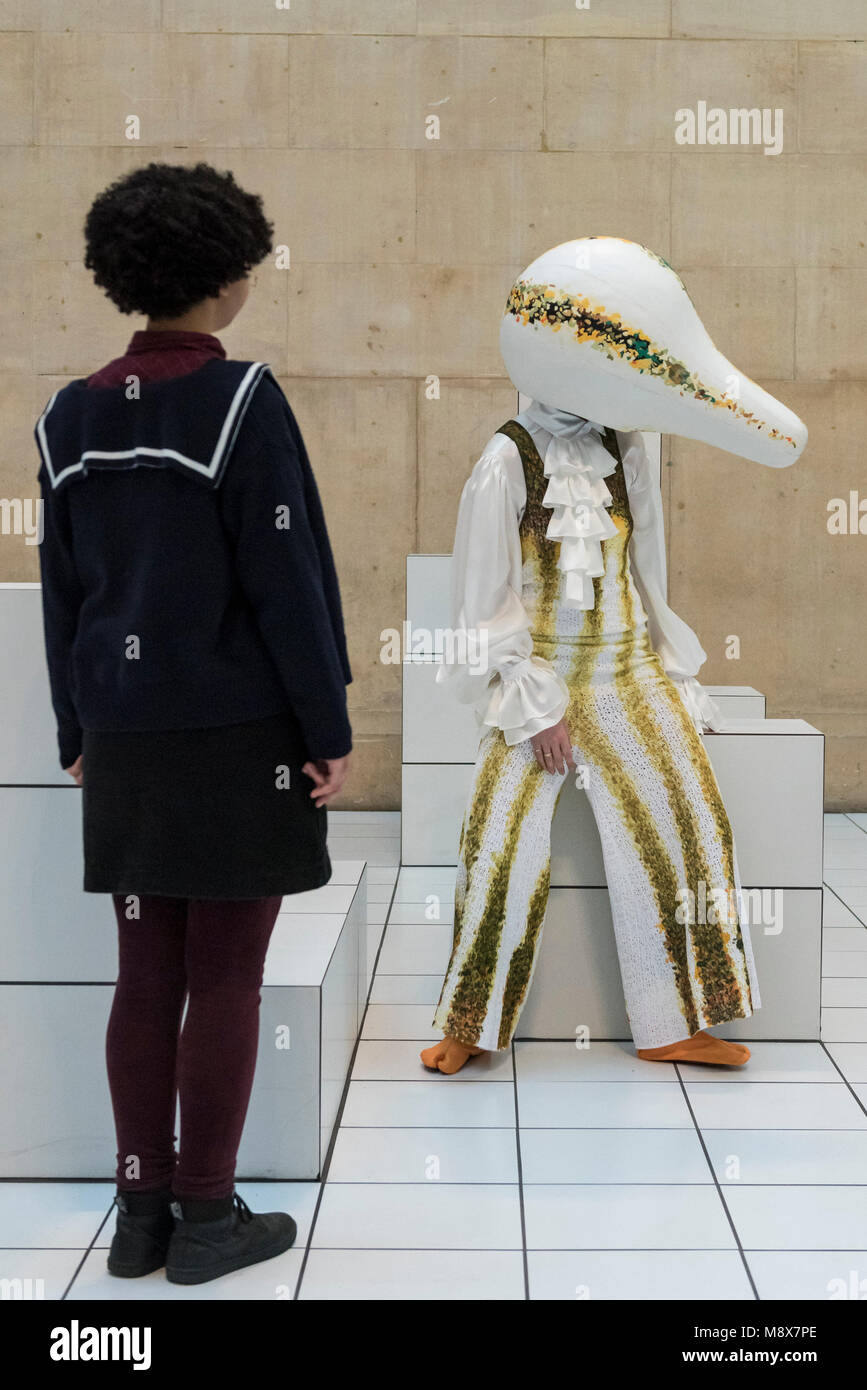 London, UK. 21 March 2018. A woman views a performer in a squash-like ...