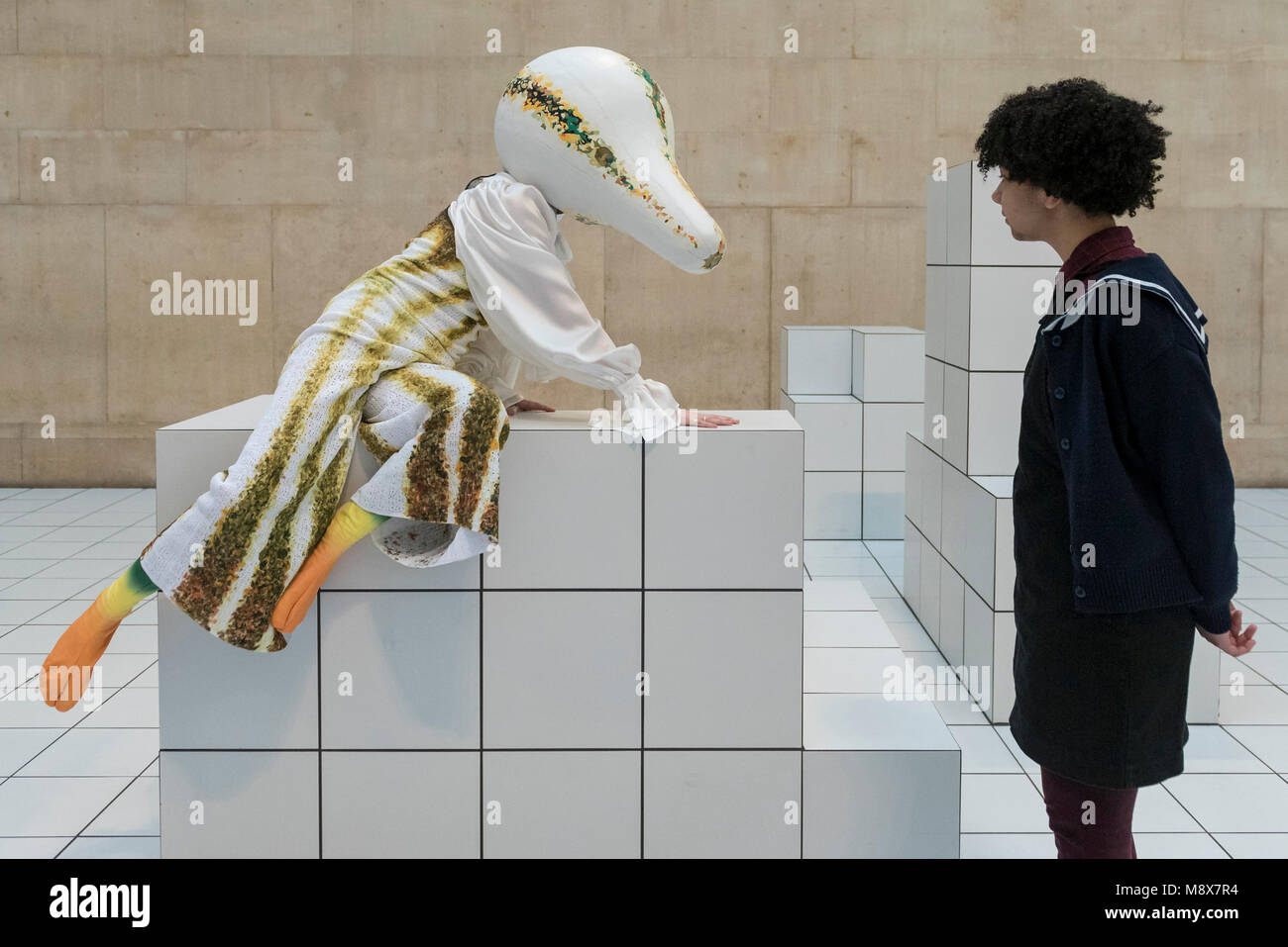 London, UK. 21 March 2018. A woman views a performer in a squash-like ...