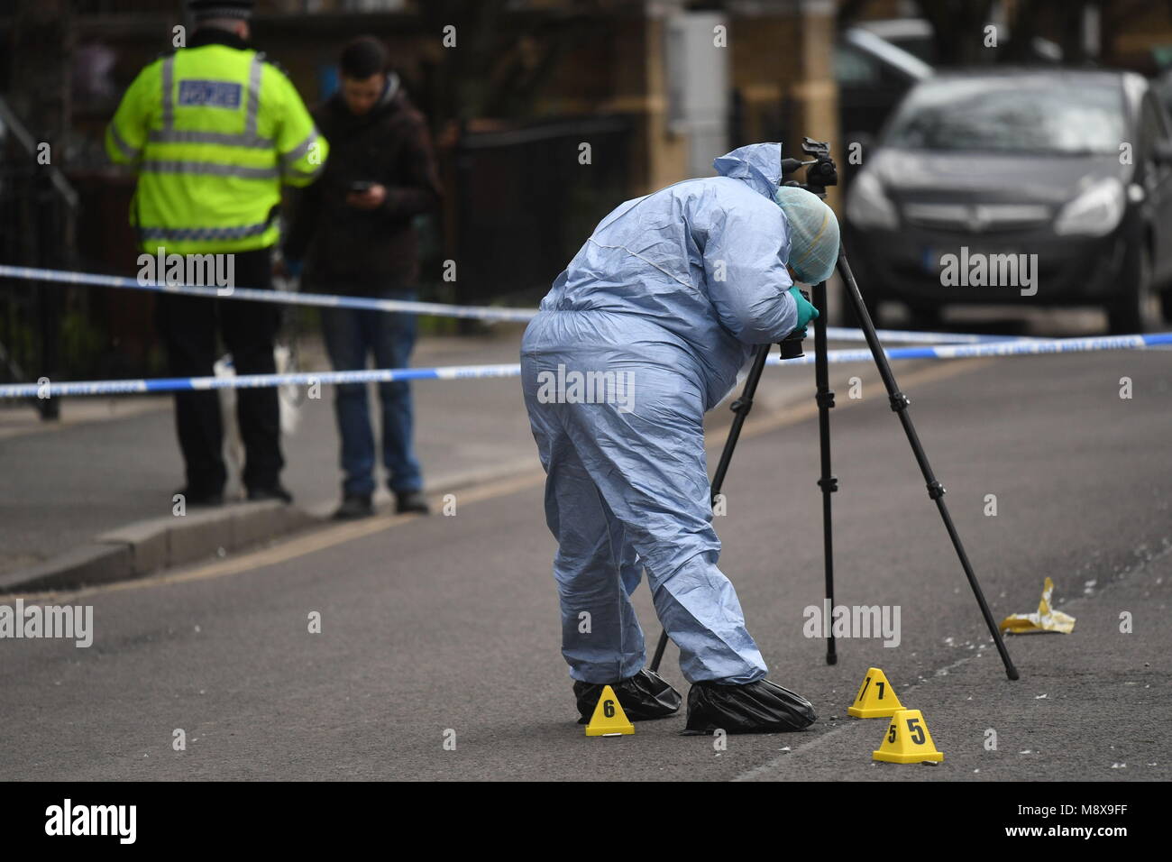 A forensic officer photographs cartridges in Mandeville Street, Clapton ...