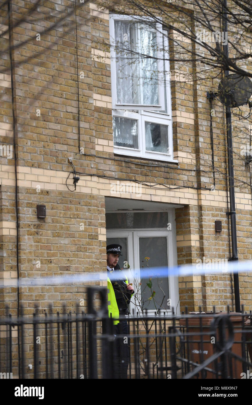 A police officer stands outside a property with a shattered window in ...