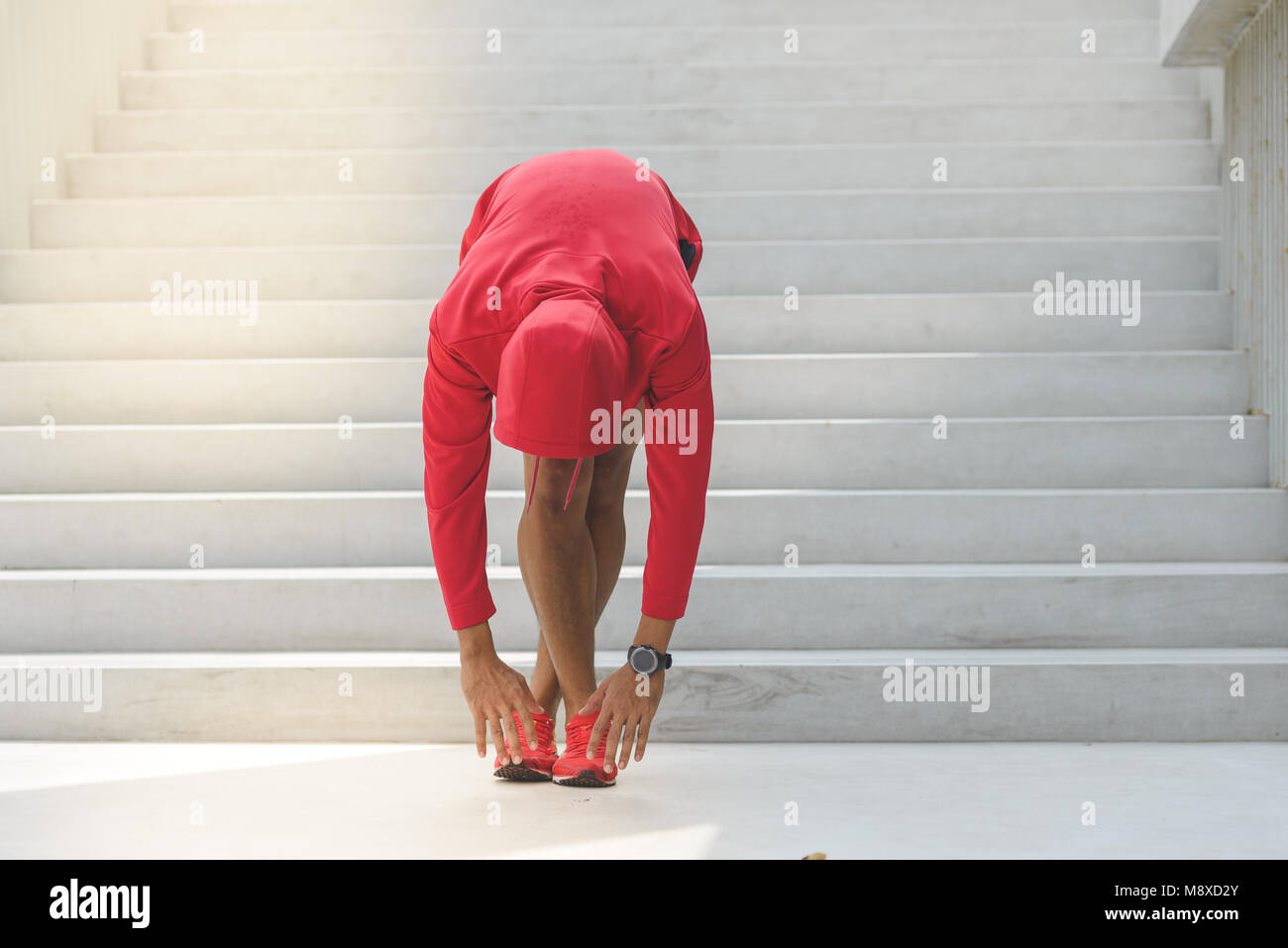 Sport man in red hood exercise at the steps outside, city lifestyle ...
