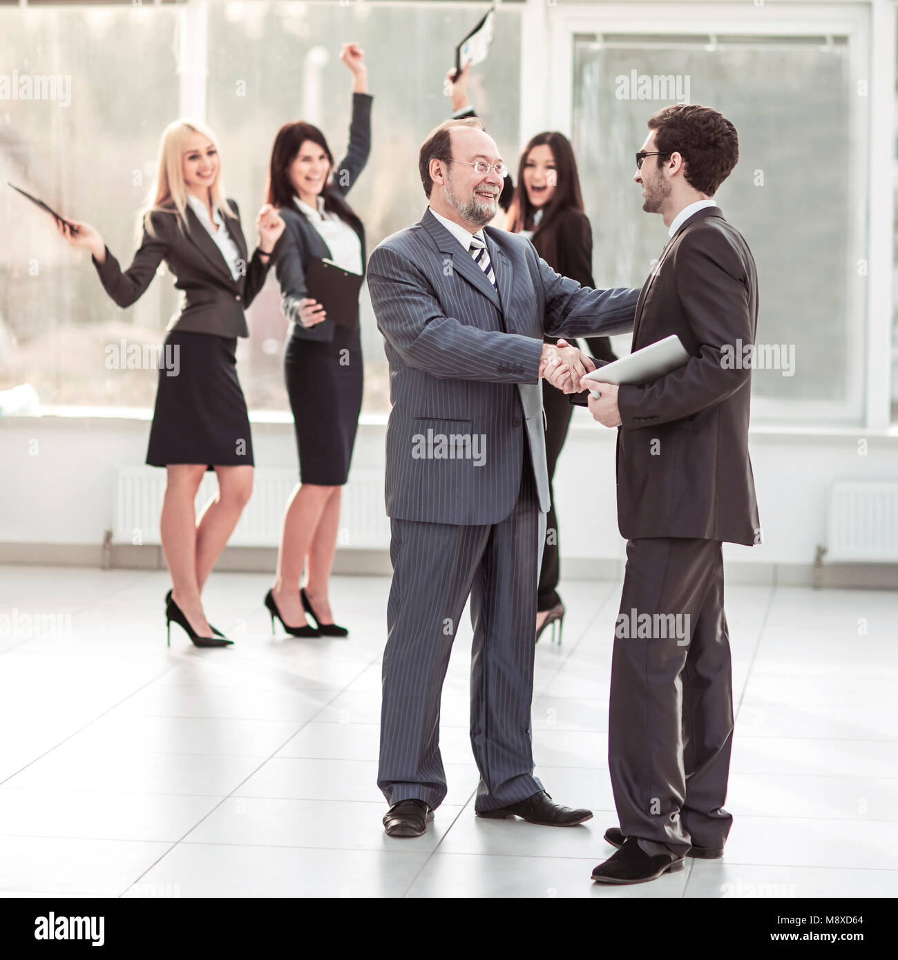 handshake of business partners on background of cheering business team ...