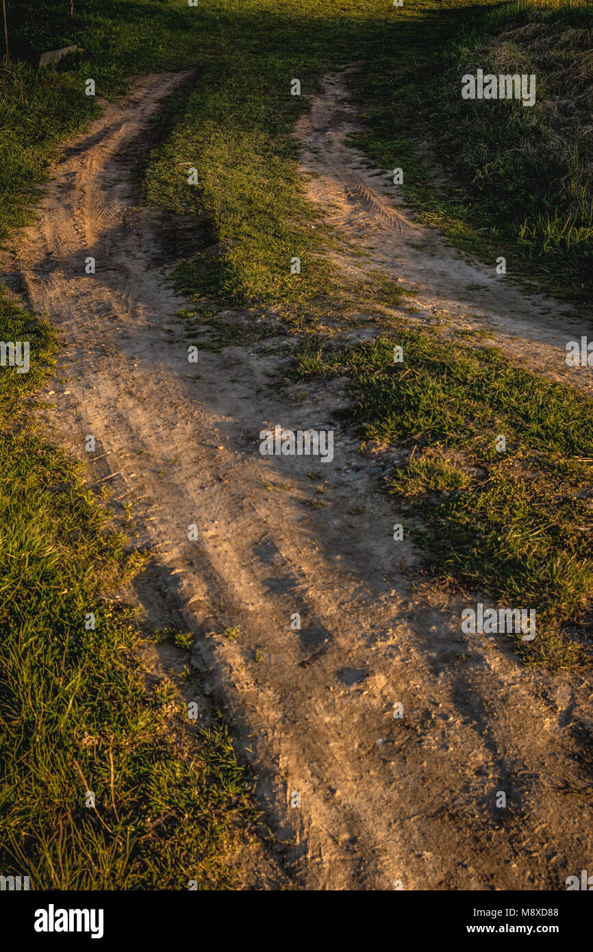 Bad shaped country road in perspective in summer with visibable car ...