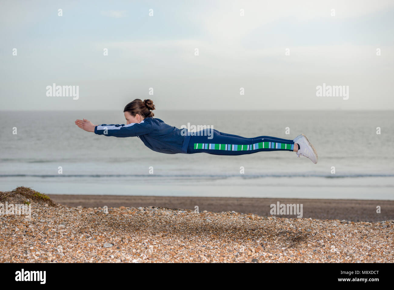 woman wearing a blue tracksuit outstretched in a dive pose levitating ...