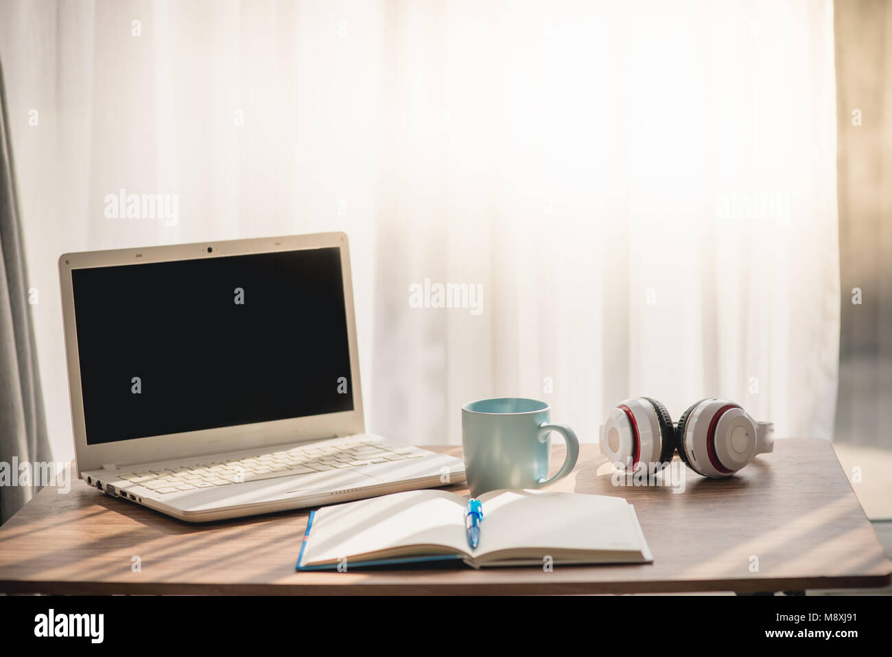 Coffee mug with notebook white laptop and headphone on table near ...