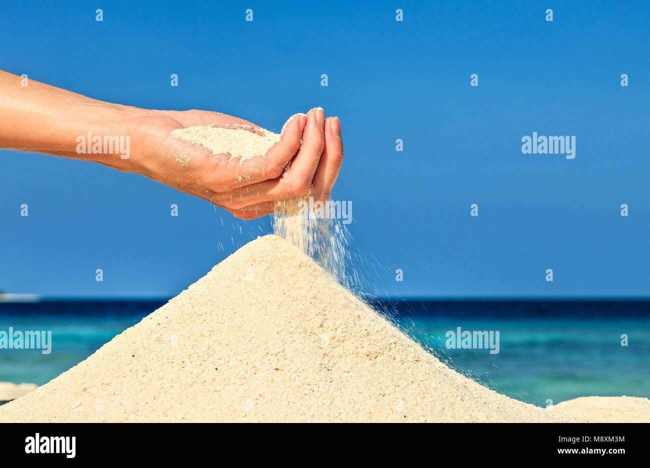 Hand is pouring coral sand on a beach Stock Photo - Alamy