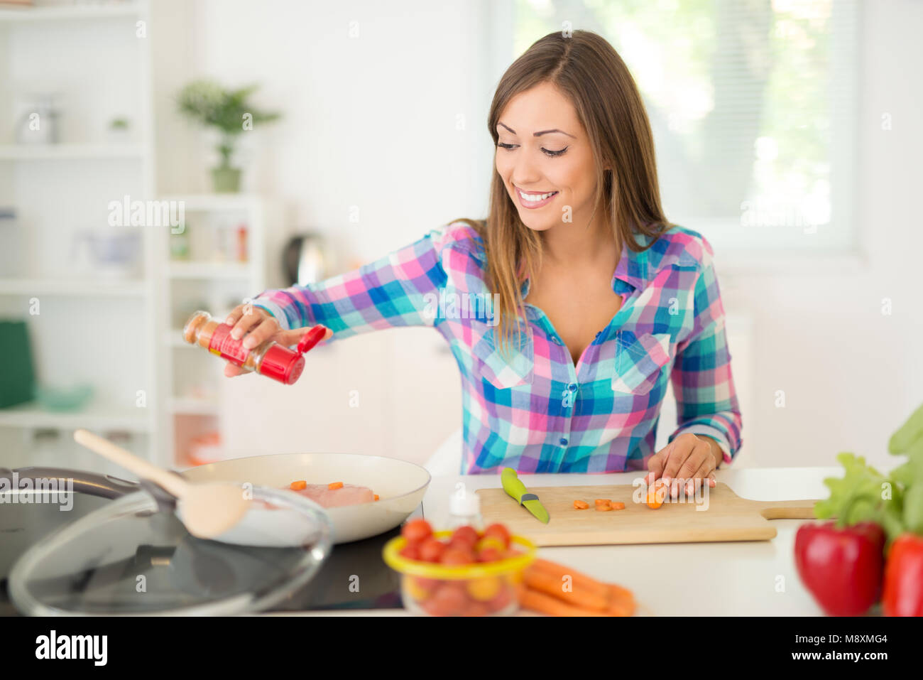 Beautiful young woman cooking healthy meal in the domestic kitchen ...