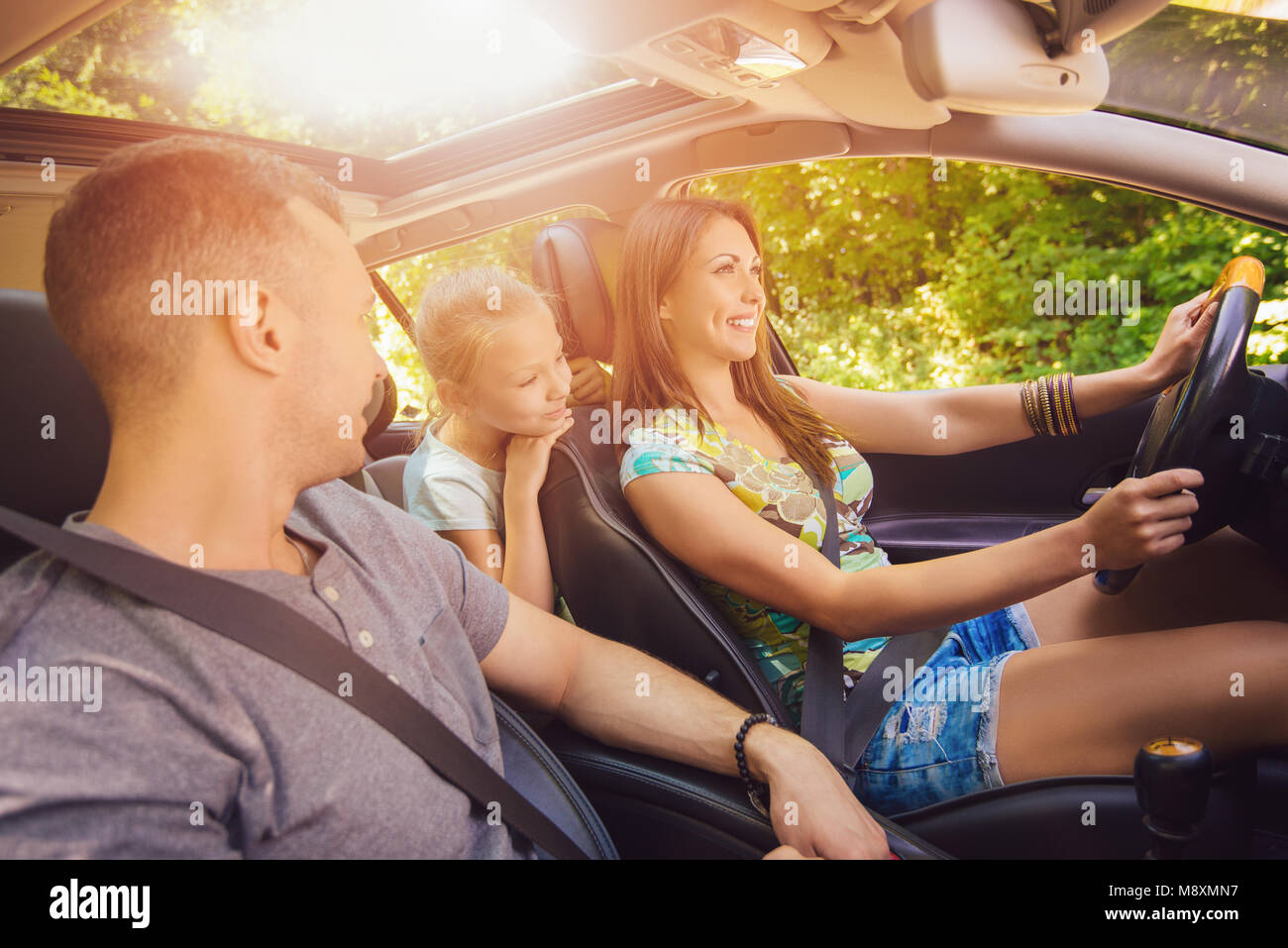 Beautiful family of three enjoying at driving a car and going on road ...