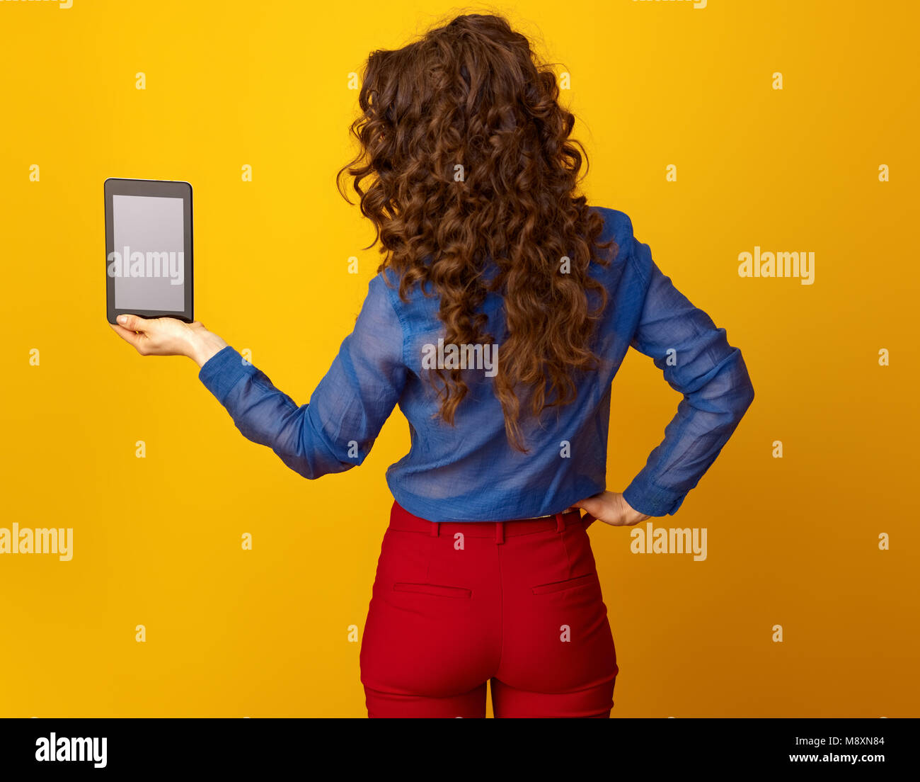 Seen from behind trendy woman with long wavy brunette hair showing ...