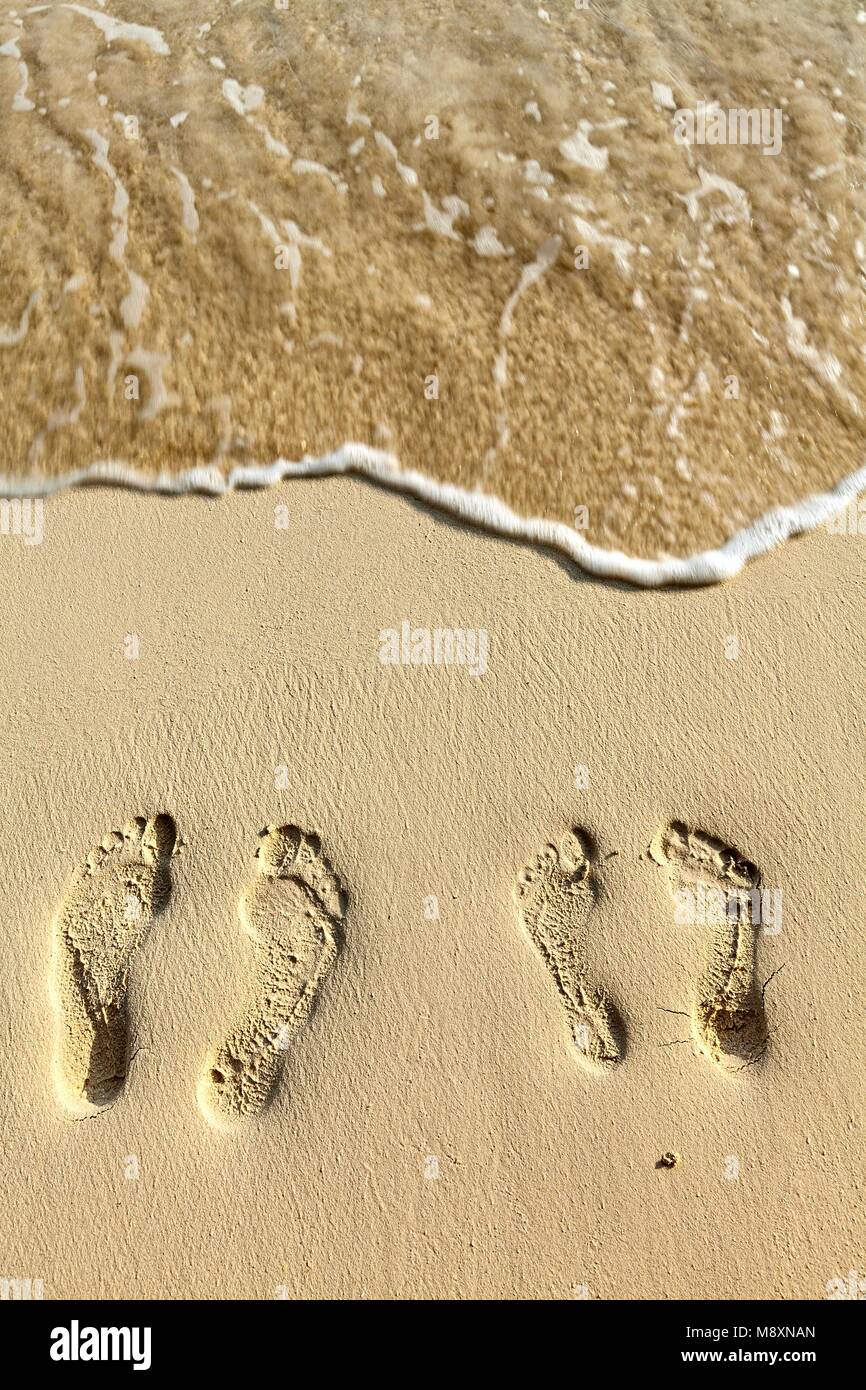 Two pairs footsteps on the coral sandy beach Stock Photo - Alamy