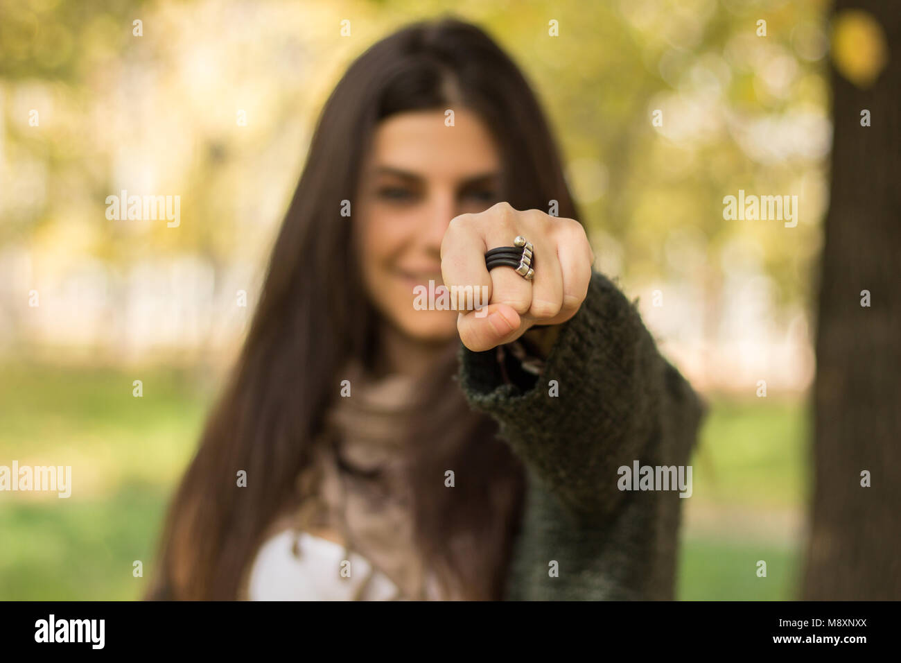 Young woman making clenched fist sign with her hand in the forest in ...