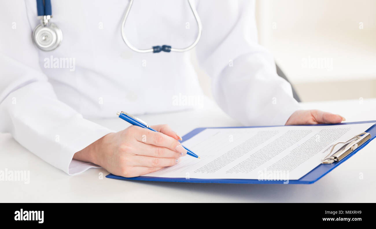 Female doctor hands writing on sheet in a clipboard with a pen Stock ...