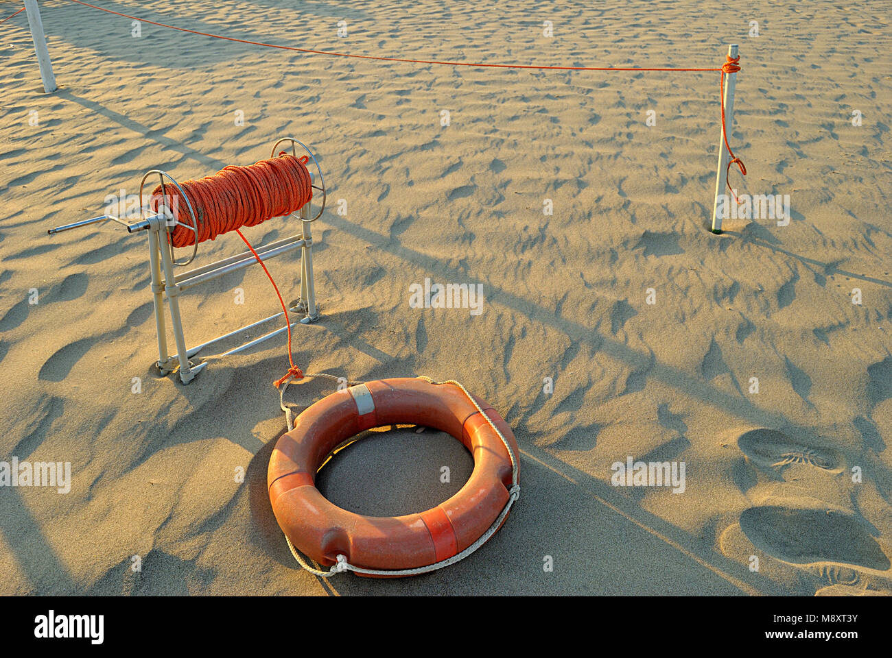summer sea, orange lifebuoy on the beach with a lot of orange rope ...