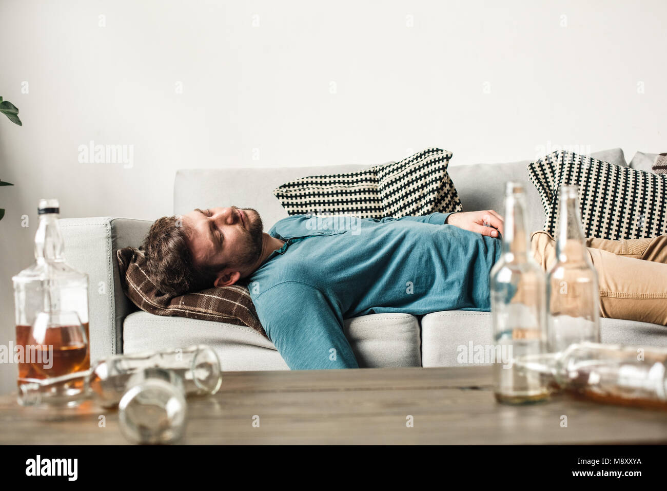 Young man at living room alcohol problems sleeping on sofa on back ...