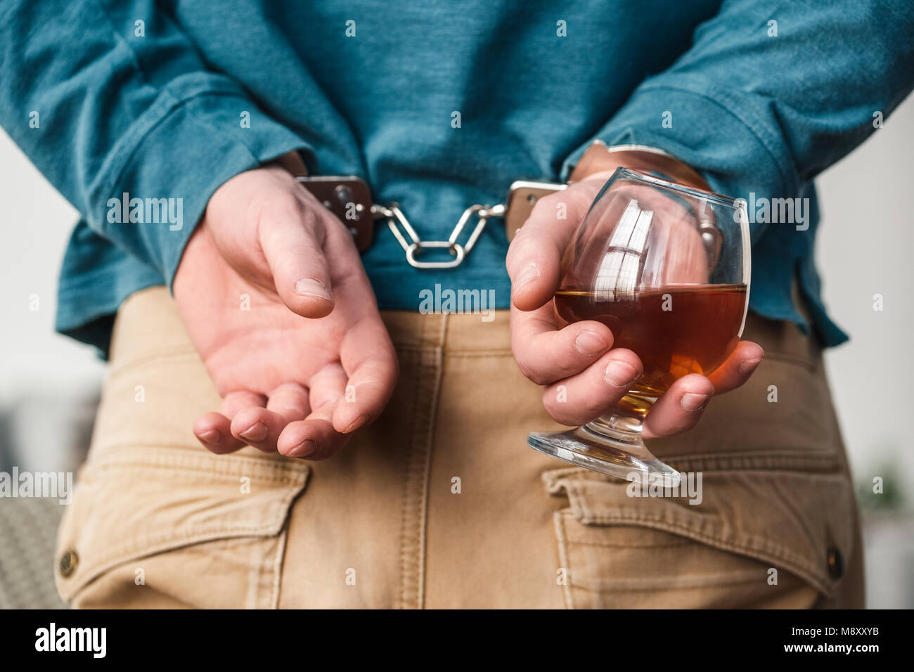 Young man at living room alcohol problems hands behind in handcuffs ...