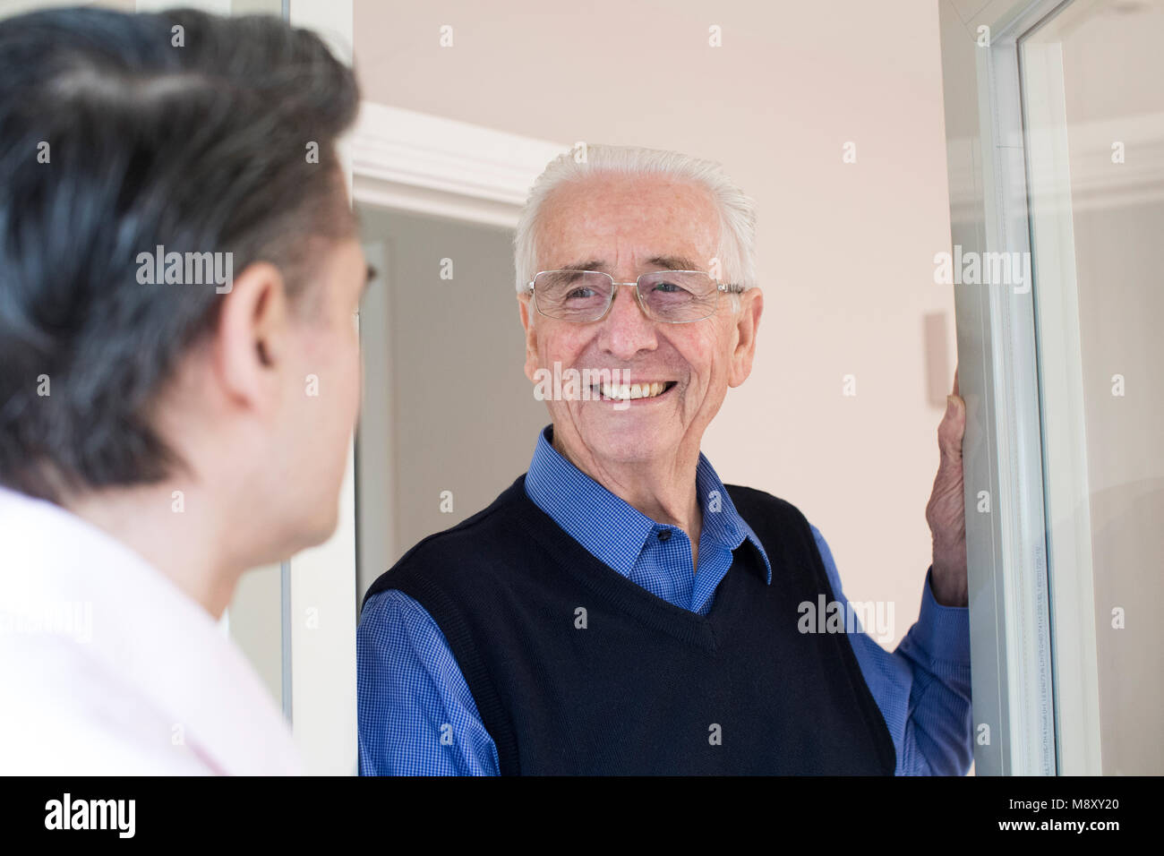 Man Checking On Elderly Male Neighbor Stock Photo - Alamy