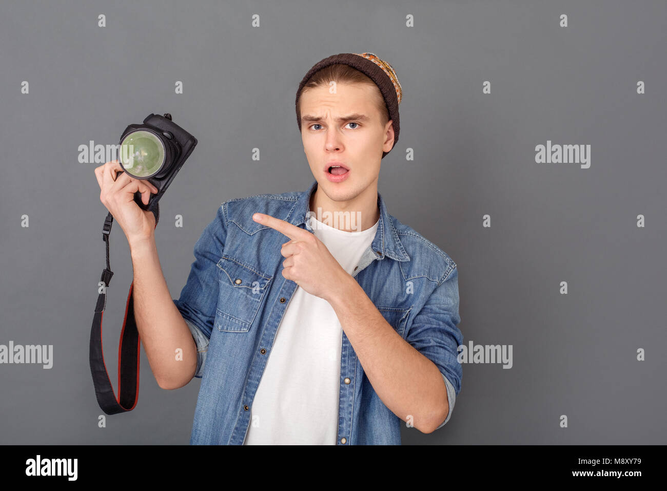 Young guy photographer wearing jeans jacket and hat studio isolated on ...