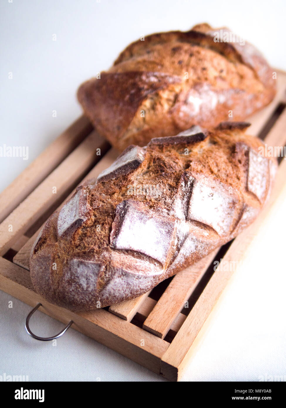 Top view of two whole country breads on a cutting board and white ...