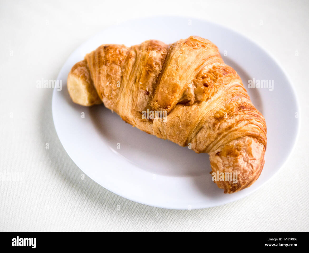 Horizontal view from above of a single French croissant on a white ...