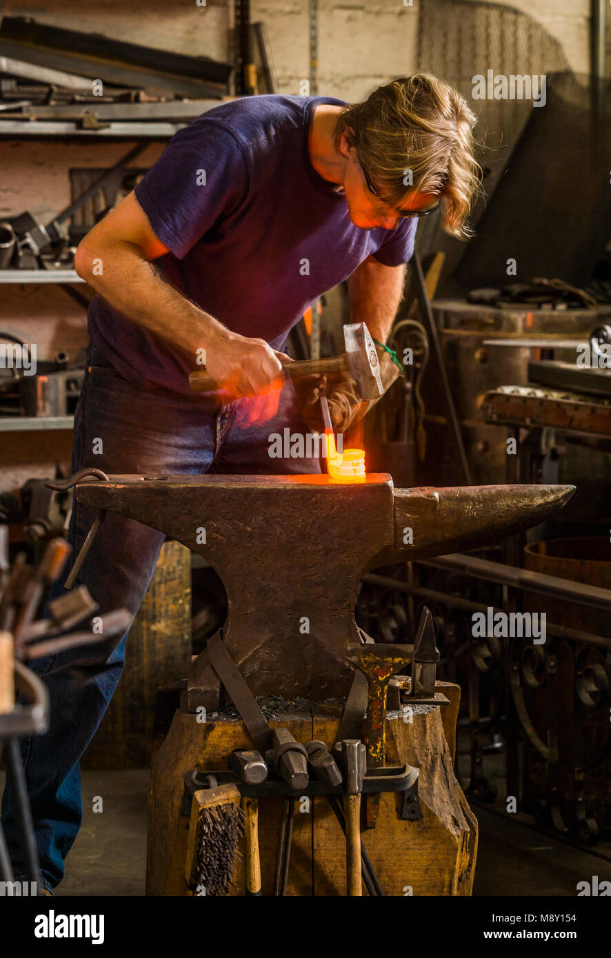 A man working in a blacksmith workshop with hammer and anvil Stock ...