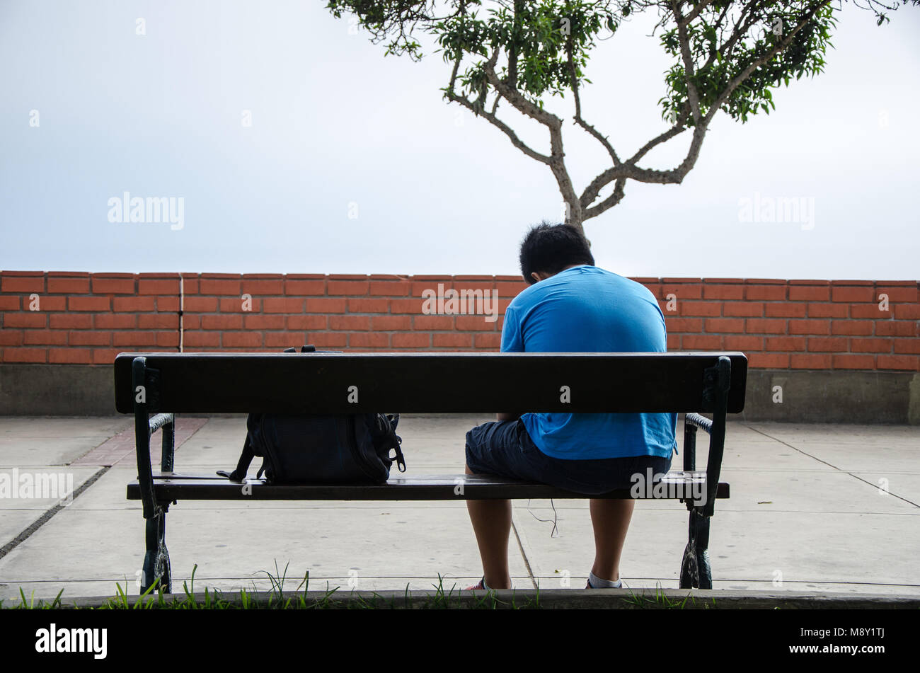 Child sitting on his back on a bench in the park Stock Photo - Alamy
