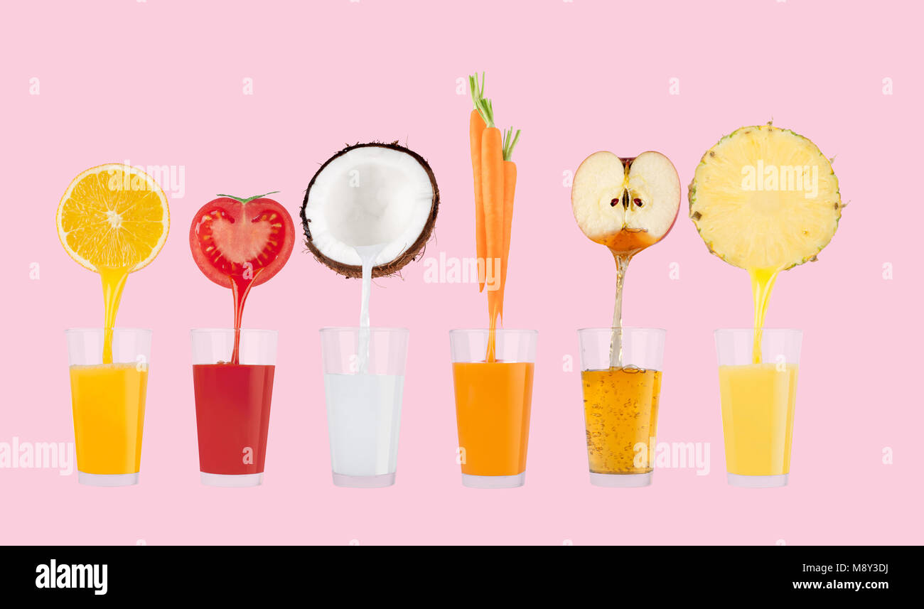 Fresh juice pours from fruits and vegetables in a glass on pastel pink ...