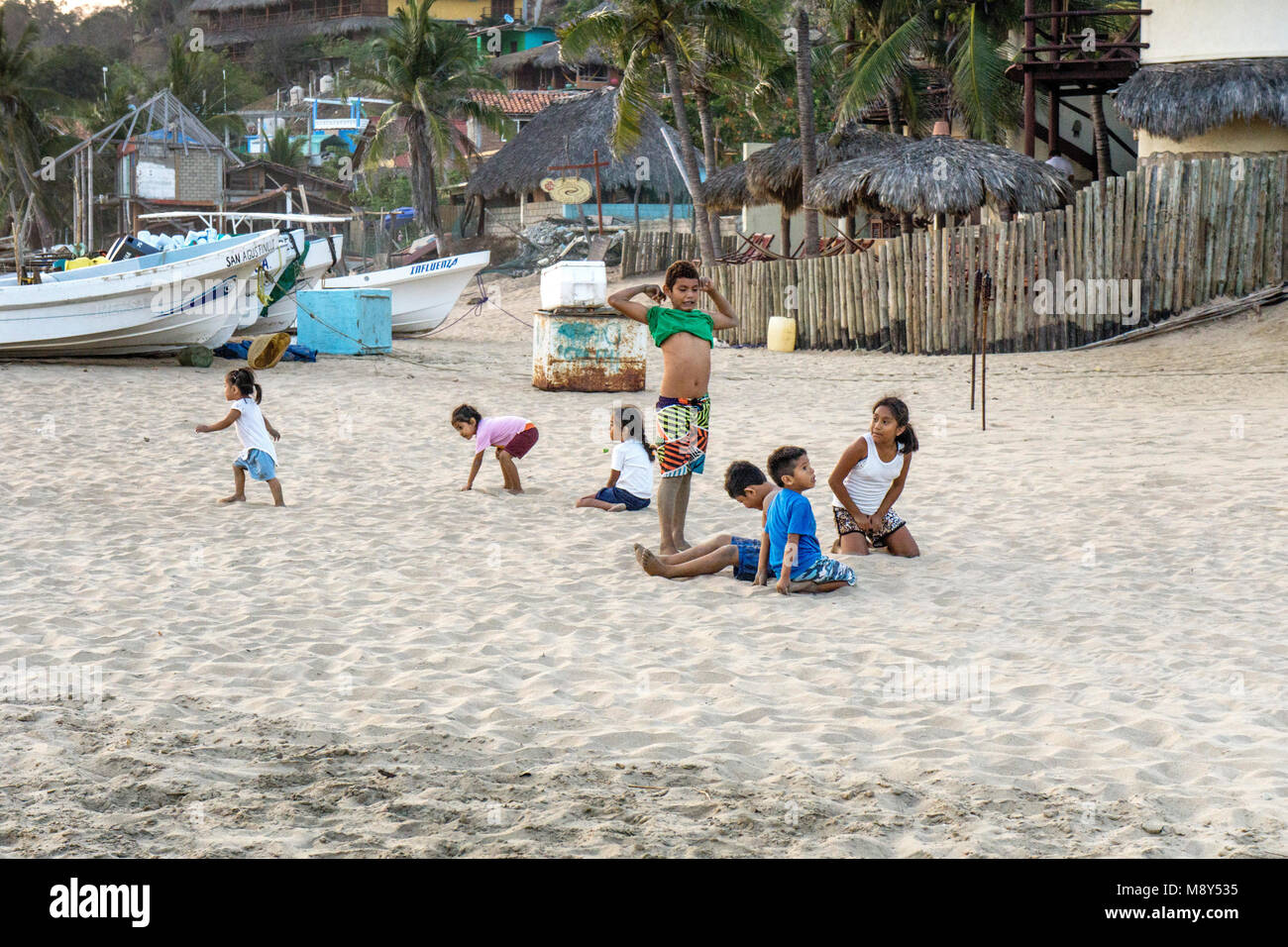 group of Mexican children from toddlers to tweens play in sand near ...