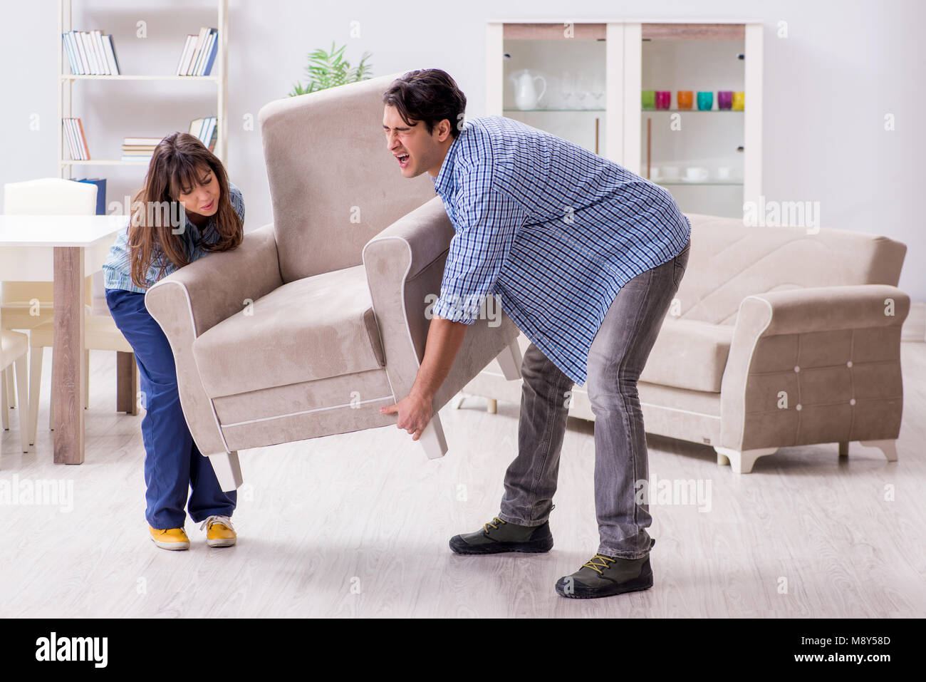 Man moving armchair in the living room Stock Photo - Alamy
