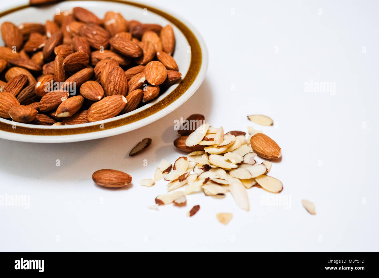 A small plate of almonds plain white background Stock Photo - Alamy