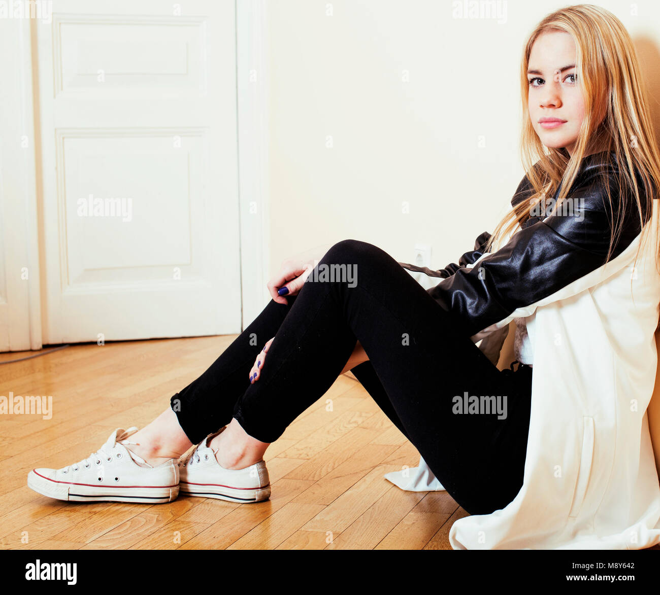 young pretty teenage blond girl sitting on floor at home despair Stock ...