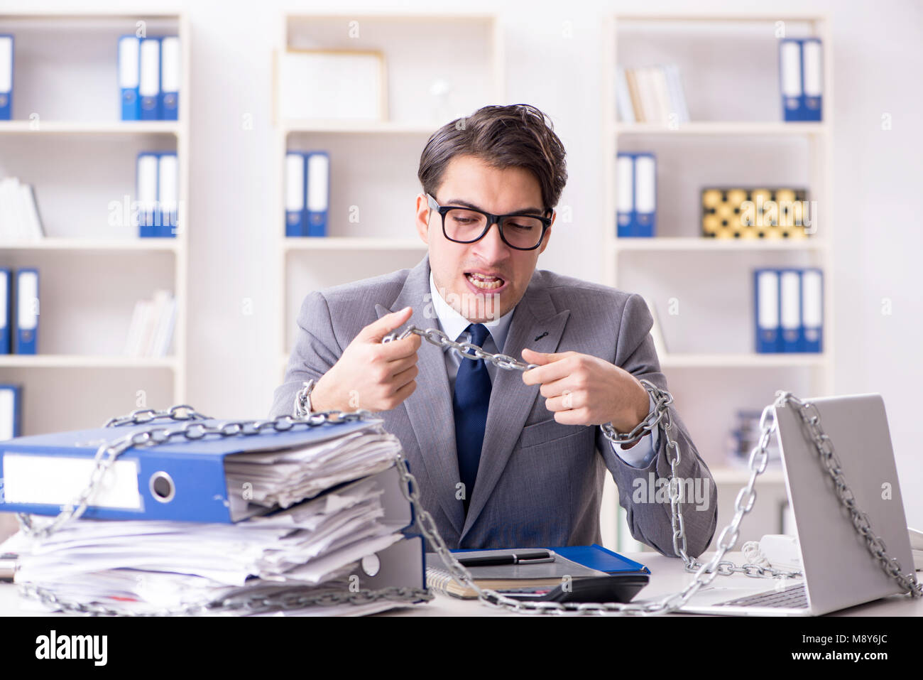 Busy employee chained to his office desk Stock Photo - Alamy