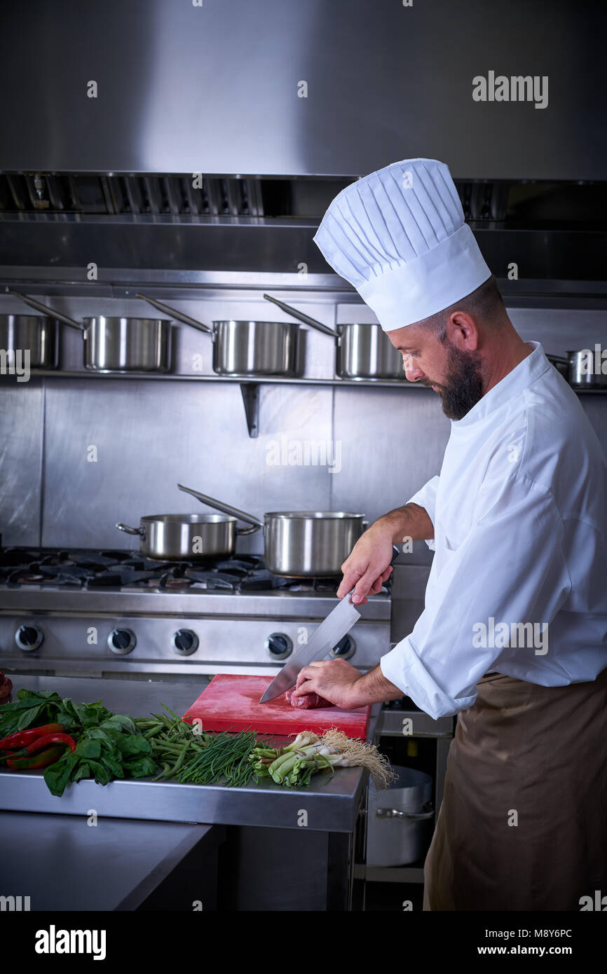 Chef cutting meat in restaurant kitchen of stainless steel Stock Photo ...