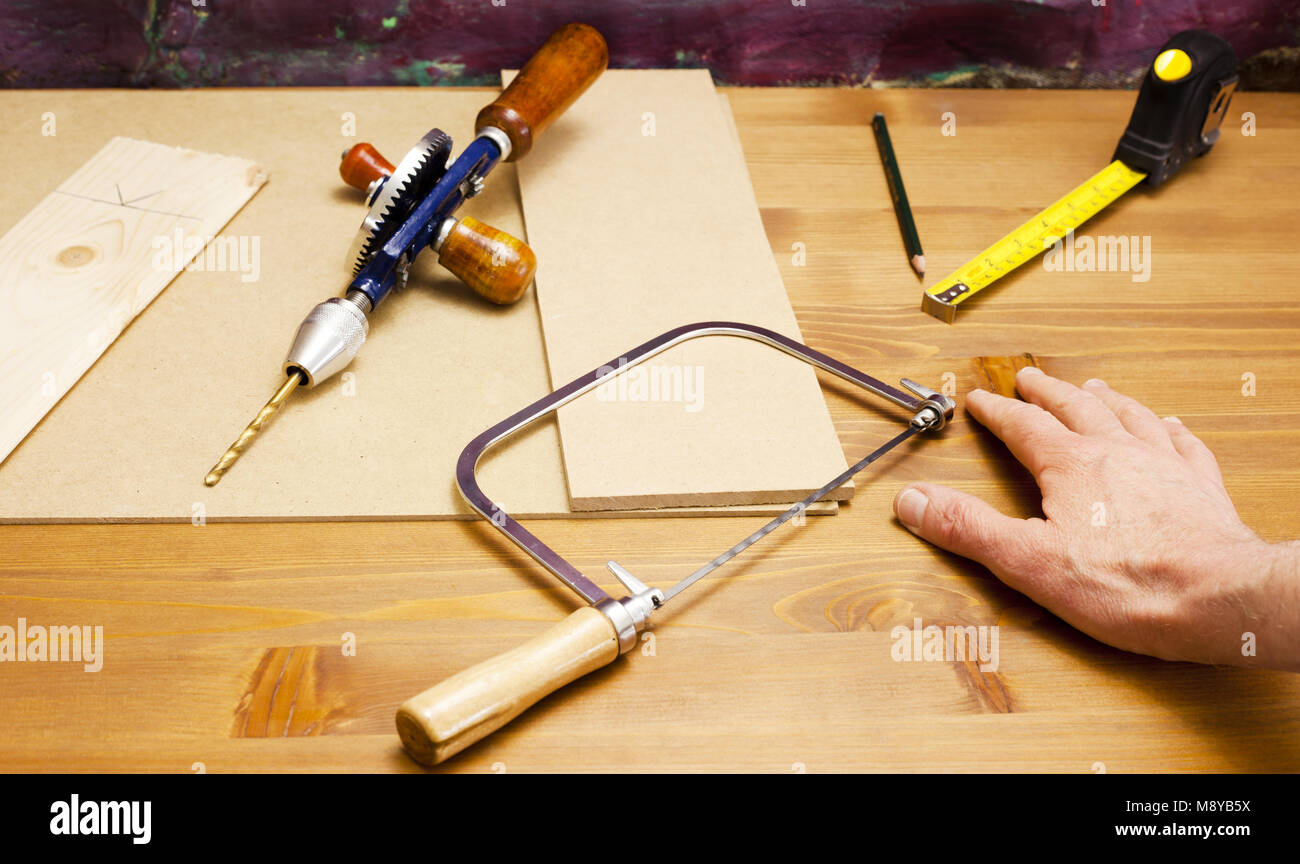 With several construction tools on bench, carpenter is about to cut ...