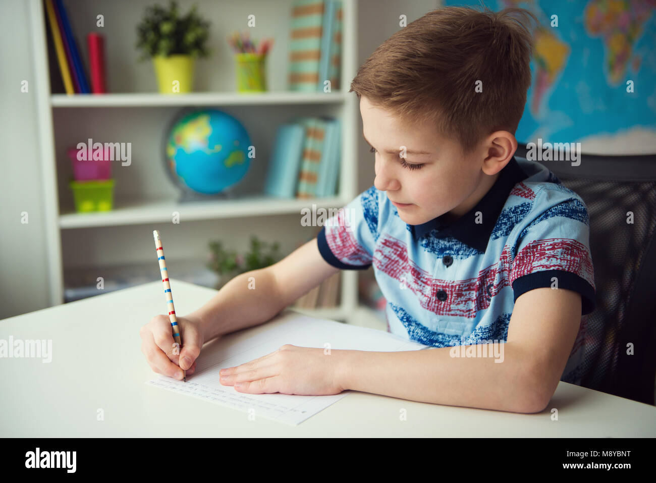 Little smart school boy making homework at desk in his room Stock Photo ...