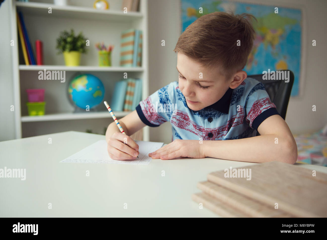 Little smart school boy making homework at desk in his room Stock Photo ...
