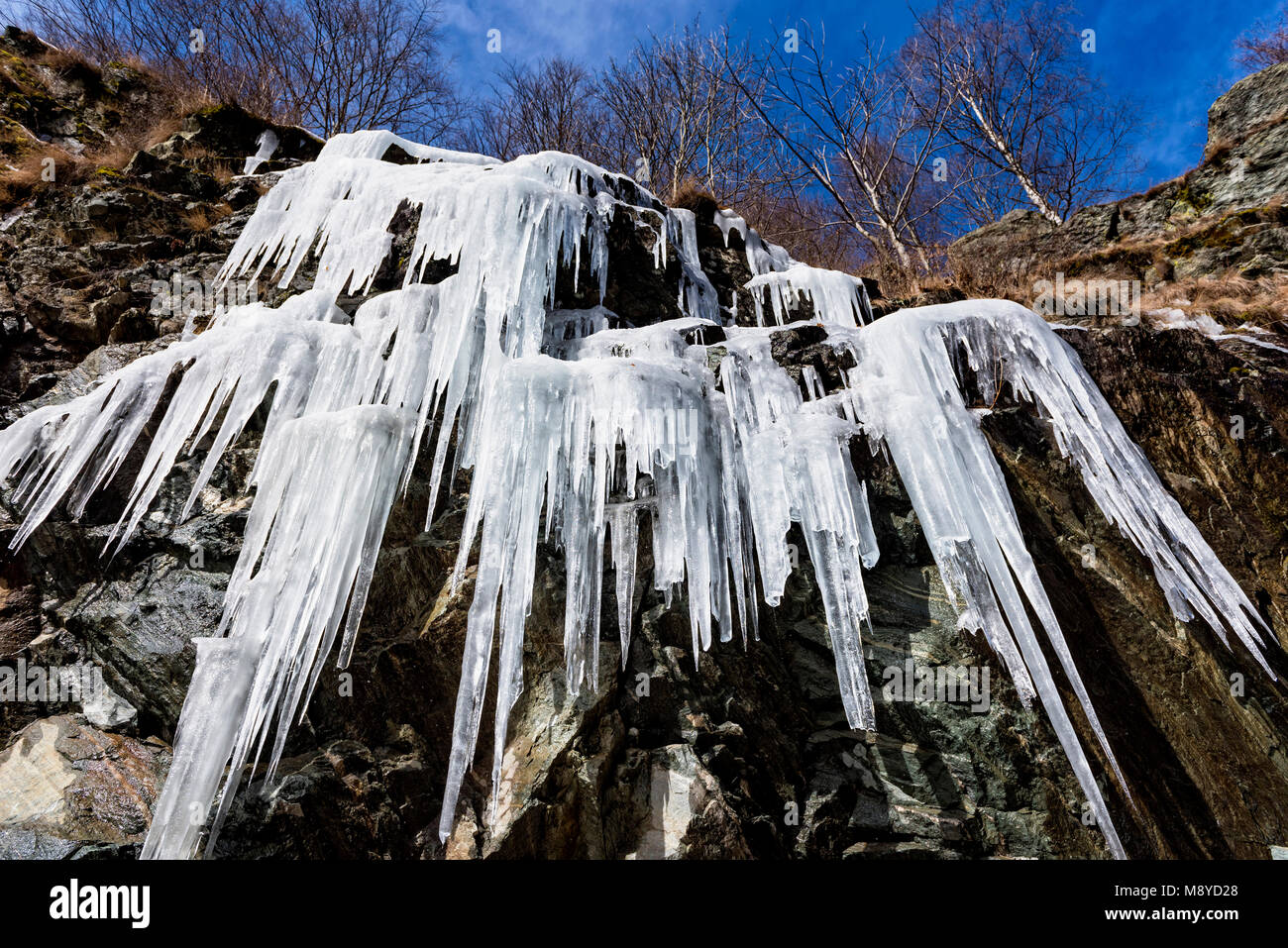 Mountain slopes covered in ice and icicles as the winter snow is ...